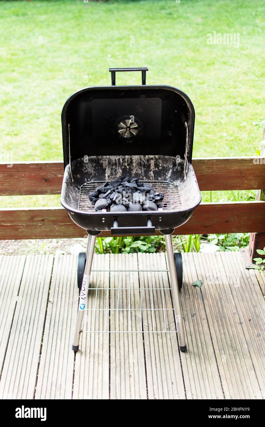 Full view of small compact barbecue grill with charcoal placed on patio ...
