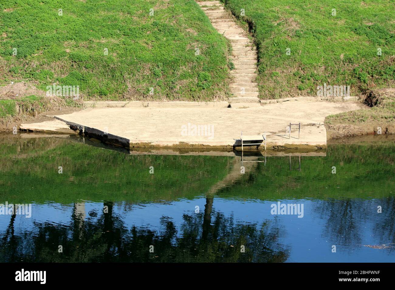 Concrete steps leading down to old concrete pier located on grass ...