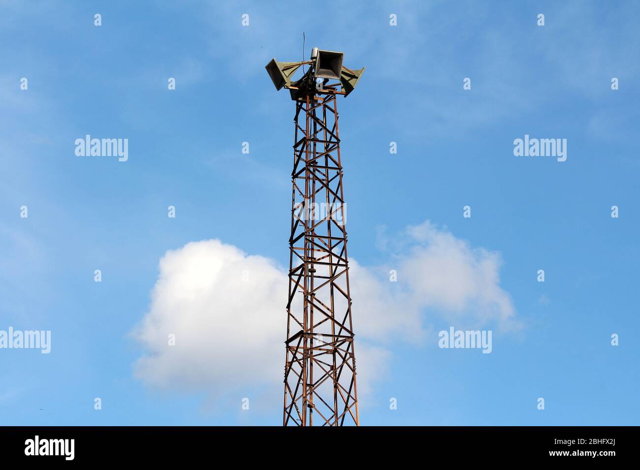 Tall partially rusted metal structure holding four large public civil ...