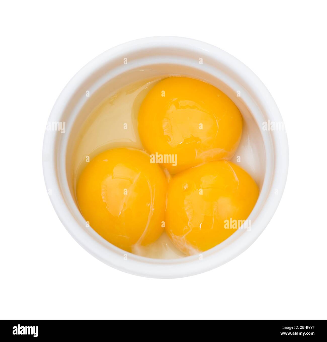 Bright yellow egg yolks in a white bowl isolated on white background ...