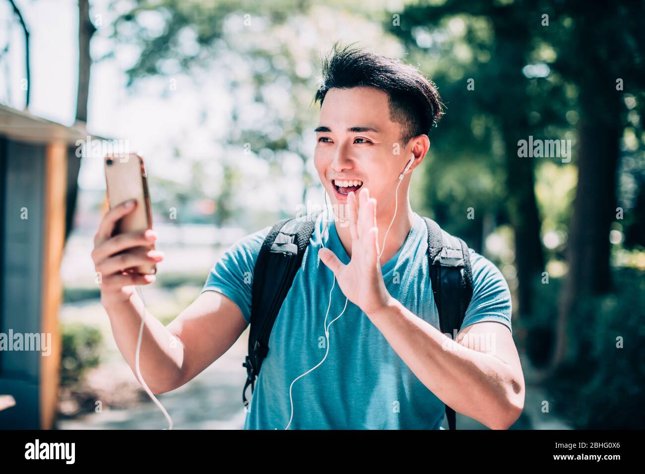 happy young man walking on street and using mobile phone for video ...