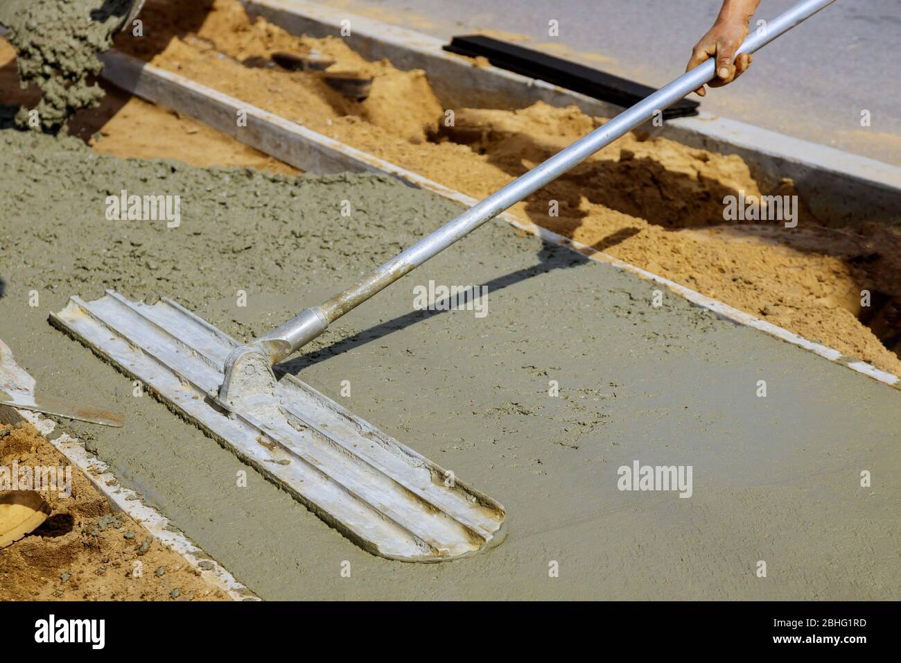 Float being used to smooth wet concrete on freshly poured sidewalks ...