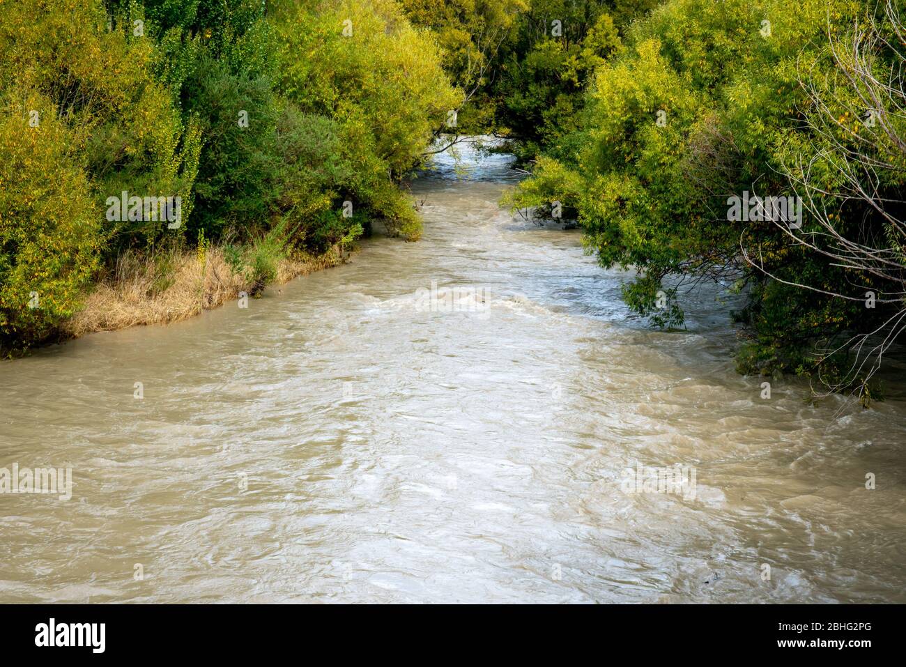 Dirty water flows rapidly down the river after days of heavy rain Stock ...