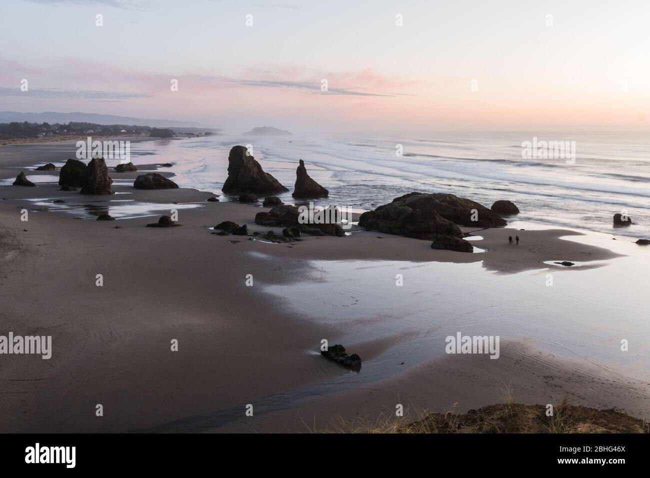 soft pinks reflecting on the wet sand as the waves move back and forth ...