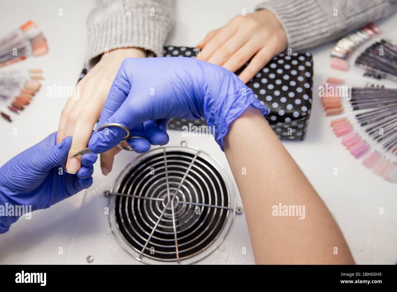 Manicurist uses scissors tool to cut cuticle on nails of client girl ...