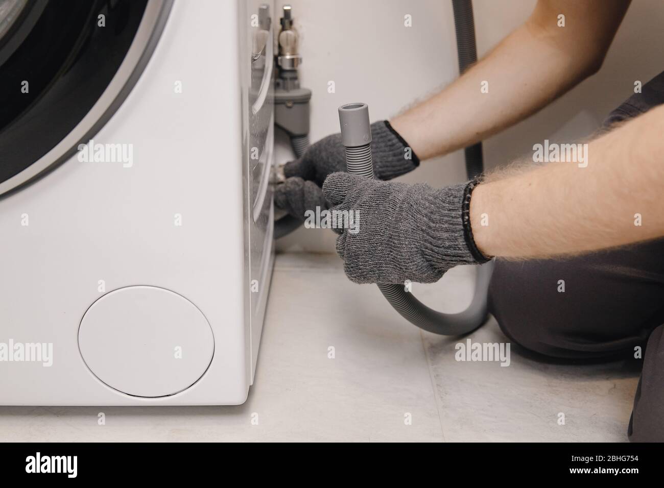 Plumber repairing washing machine, working man fixing connects pipe to ...