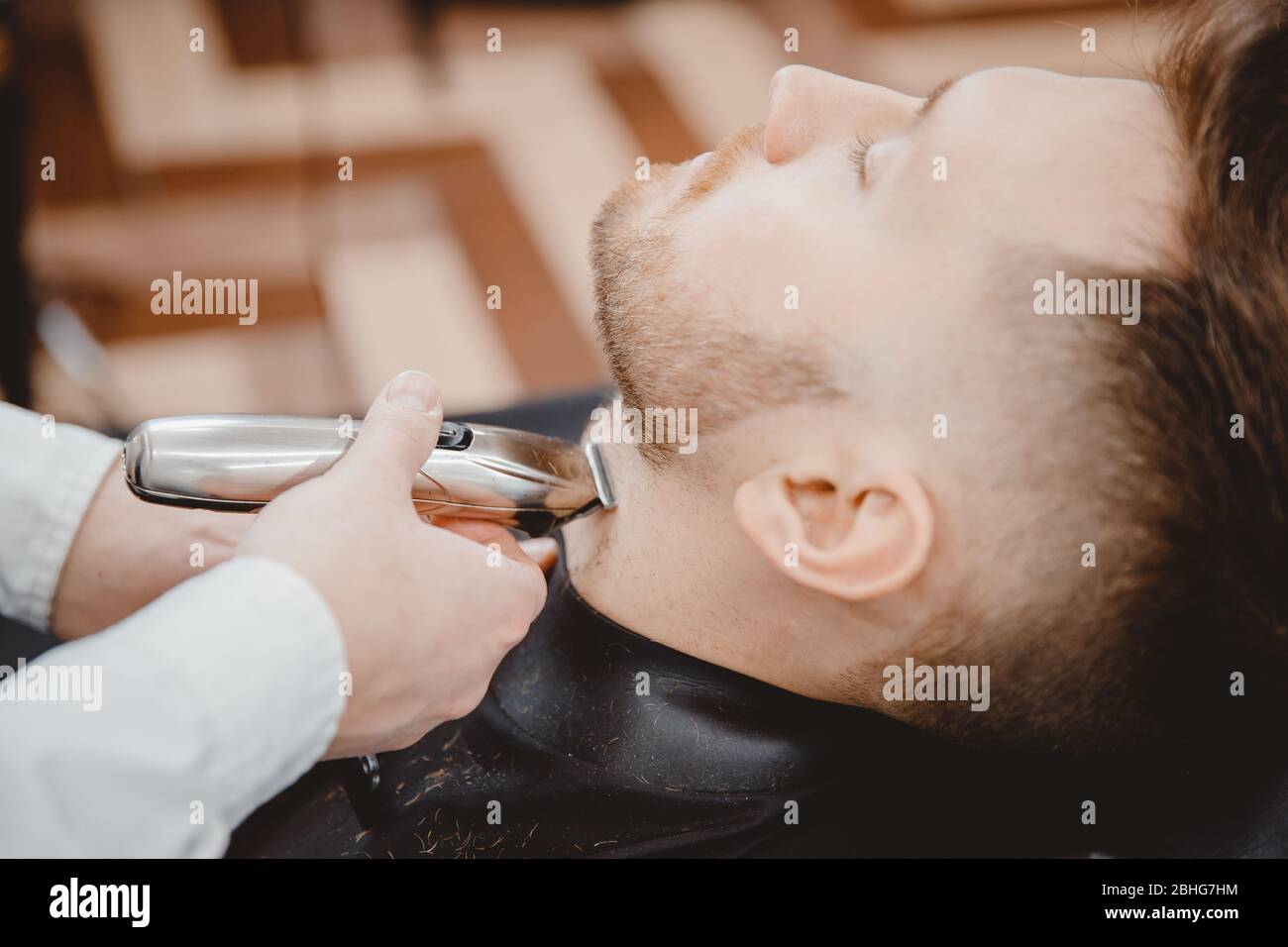 Barber shearing beard to man in barbershop framing hairline. electric ...