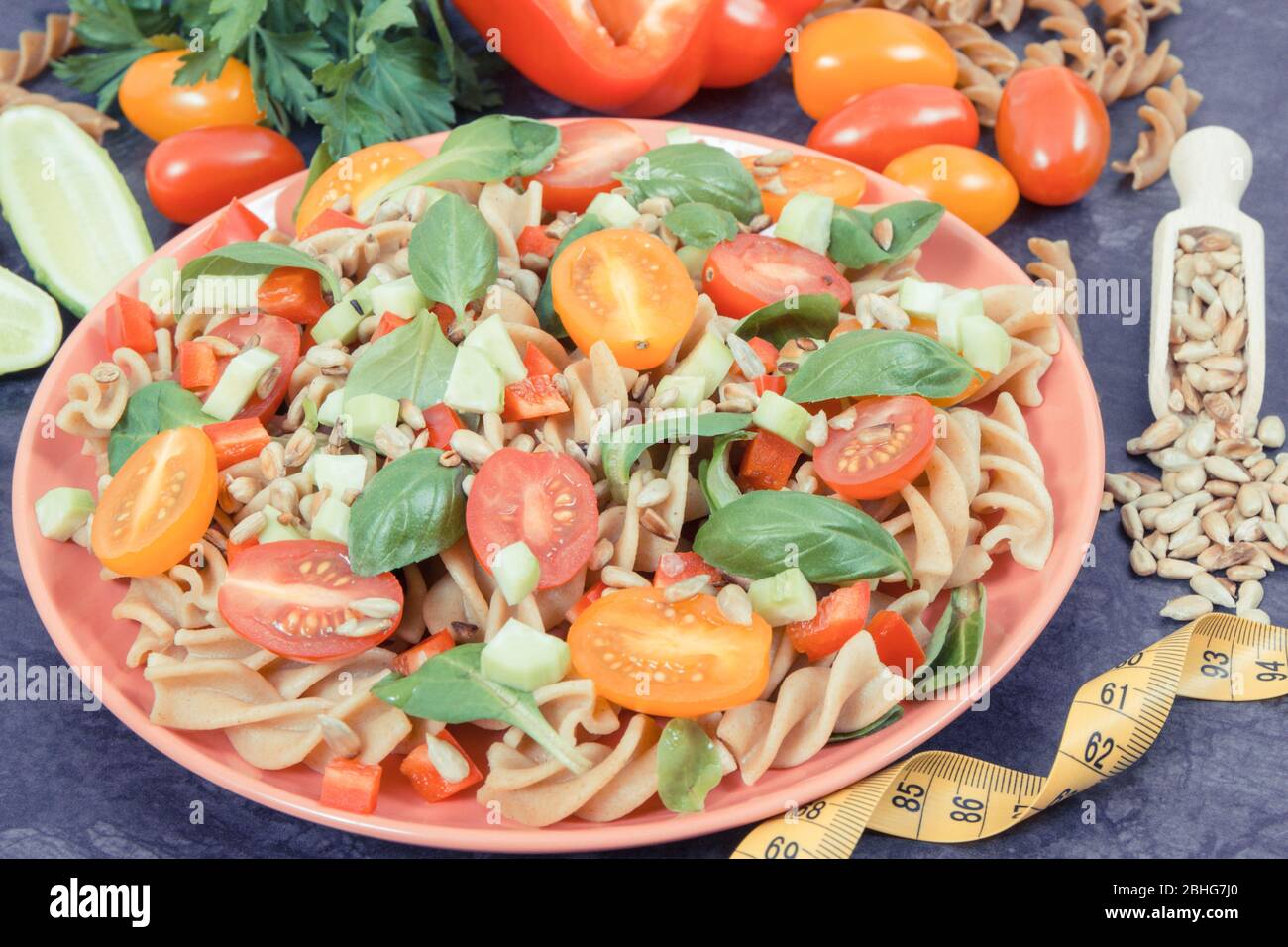 Tape measure and fresh prepared salad with wholegrain pasta and ...