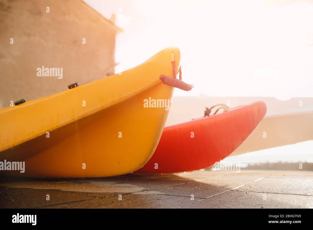 Yellow plastic kayak boats stand in parking lot, sunset light. Concept ...