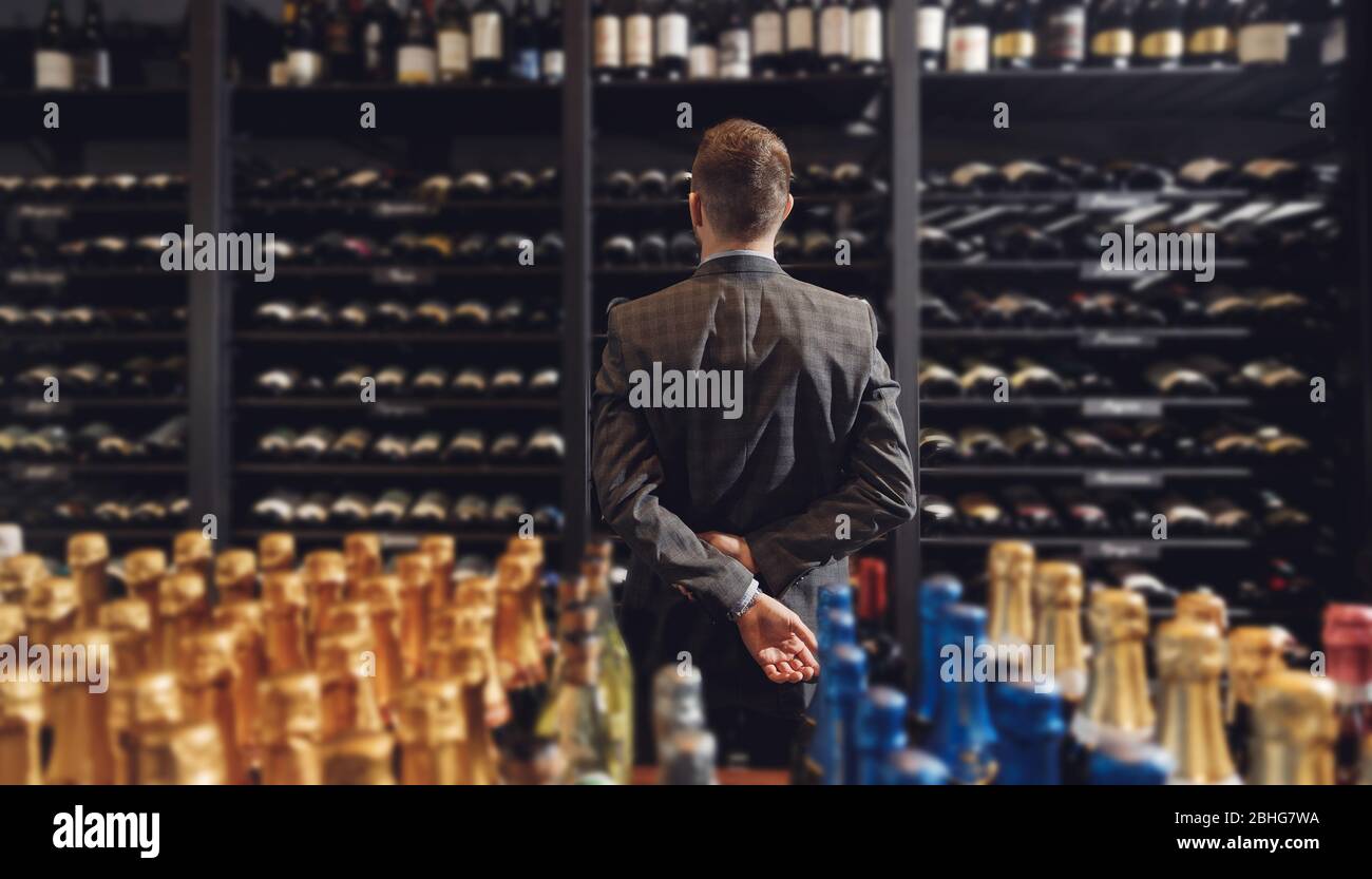 Bartender sommelier picks bottle of wine from rack in restaurant with ...