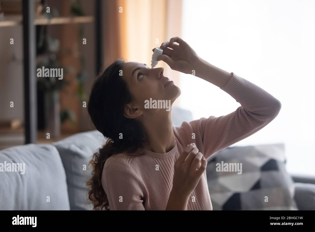 Young woman tipping back head, using medical eyes drops Stock Photo - Alamy