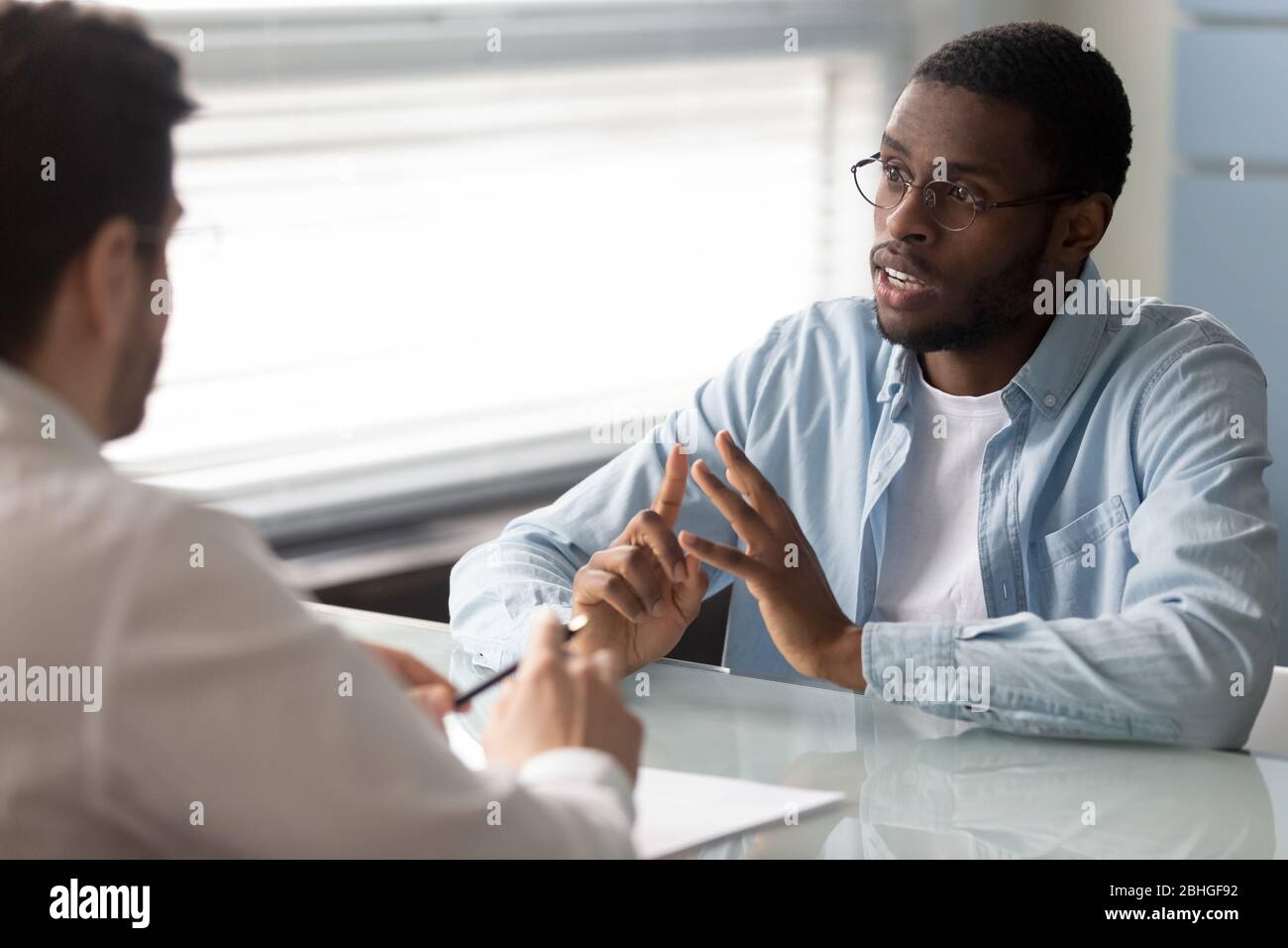 Serious african american candidate talking with businessman at job ...