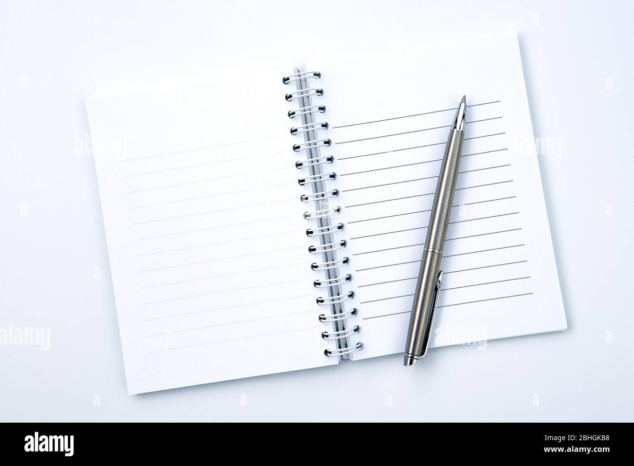 Open notebook with a pen on a white office table Stock Photo - Alamy