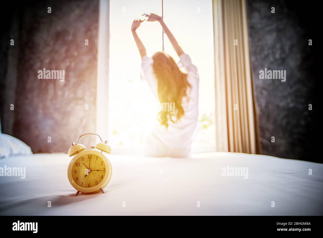 alarm clock having a good day of Asian woman waking up in her bed fully ...