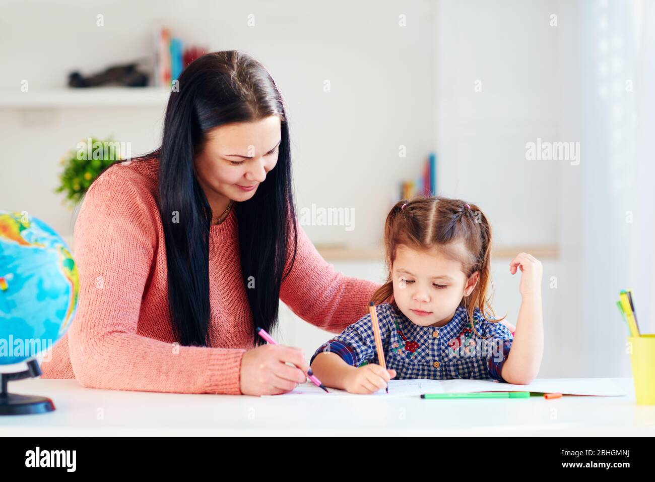 mother helping daughter to develop writing skills at home Stock Photo ...