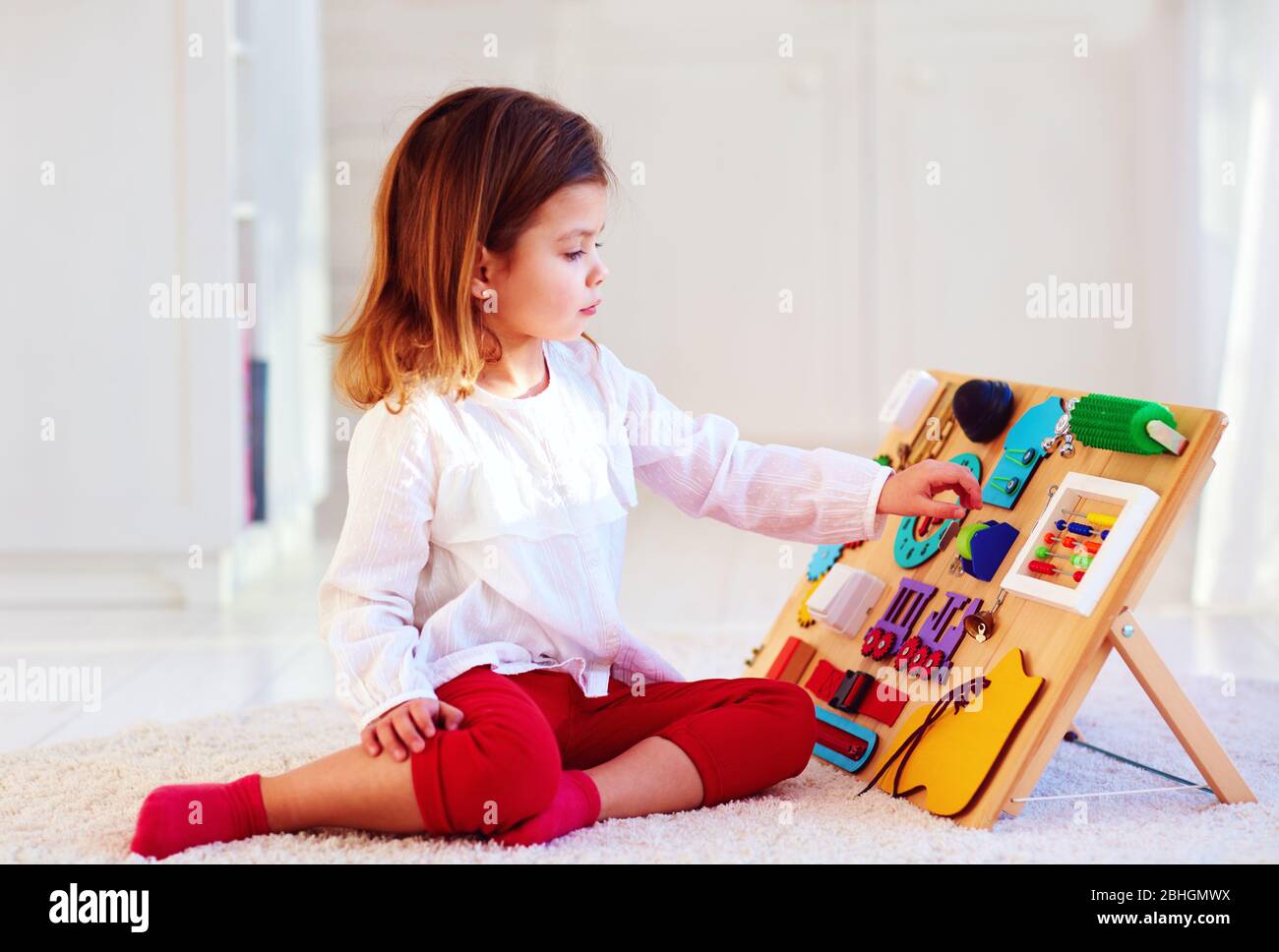 cute baby girl having fun playing with colorful wooden busy board Stock ...