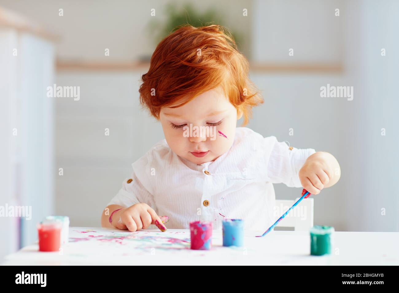 happy little baby artist drawing with colorful paints at home Stock ...