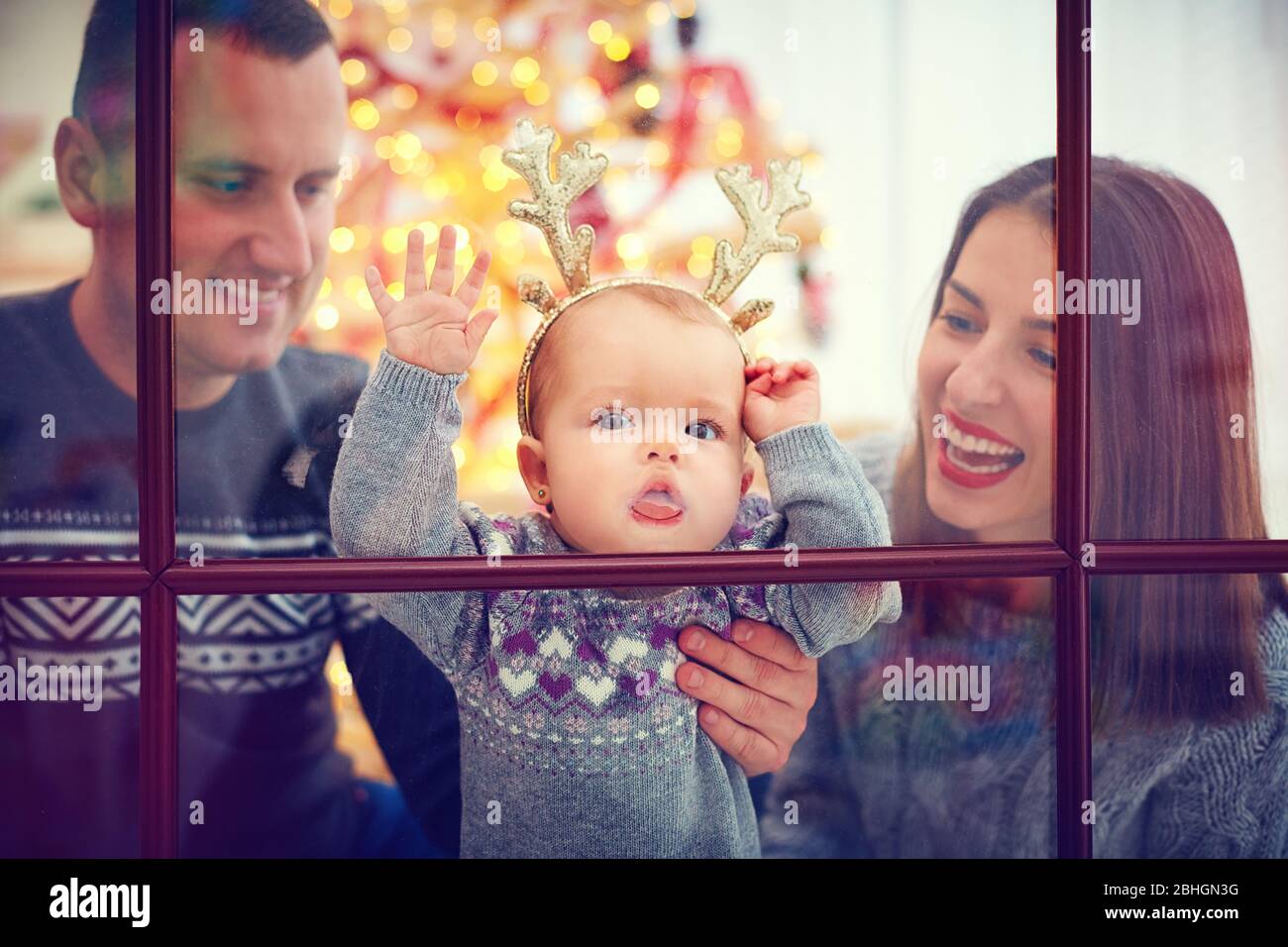 cute baby girl licking the window, enjoying christmas holidays with the ...