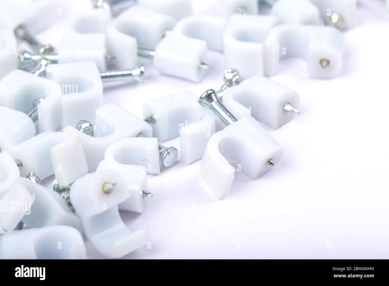 Close up of Plastic cable clips with galvanized steel nails on white ...