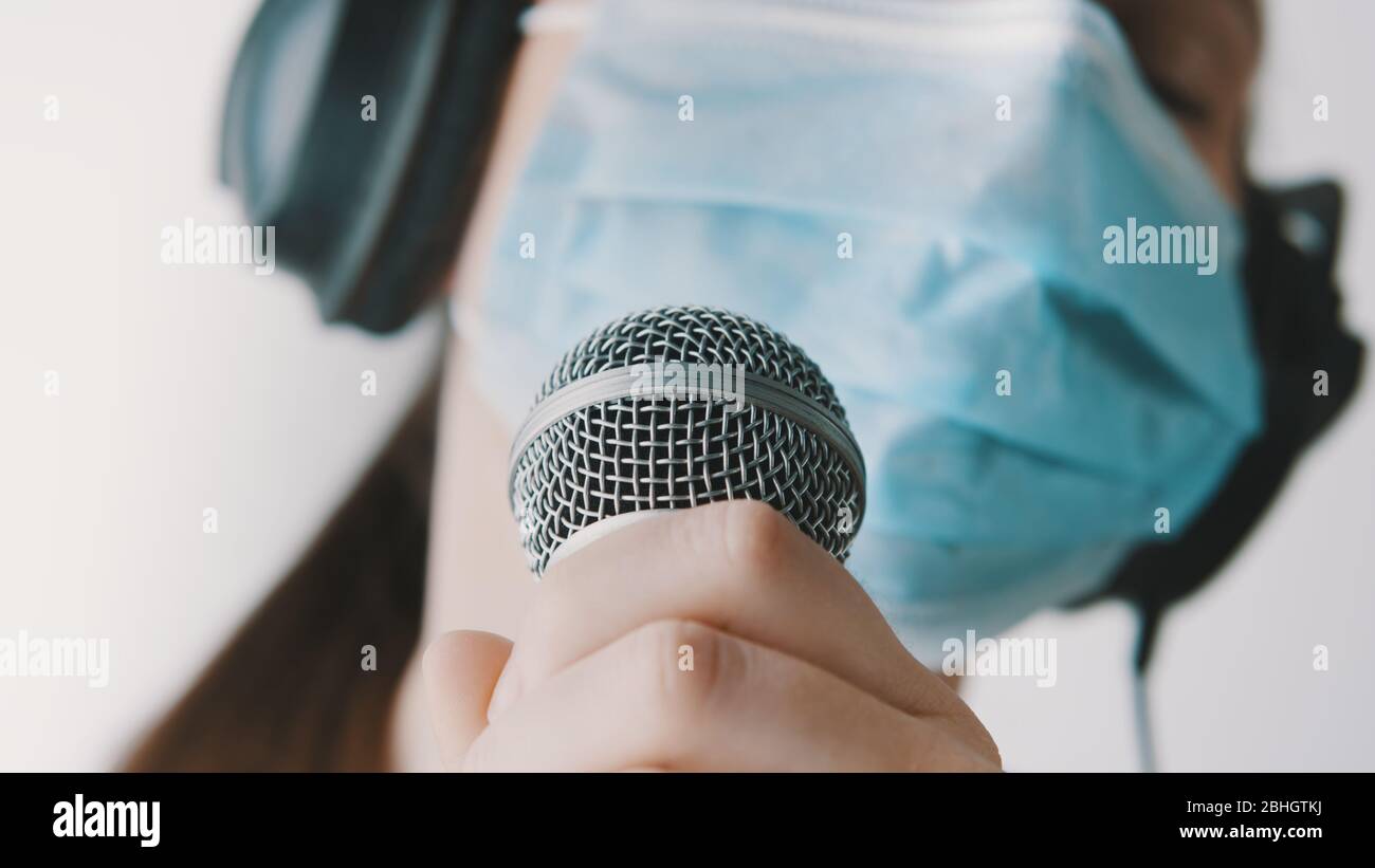 Young singer singing in the microphone fith face mask in home studio ...