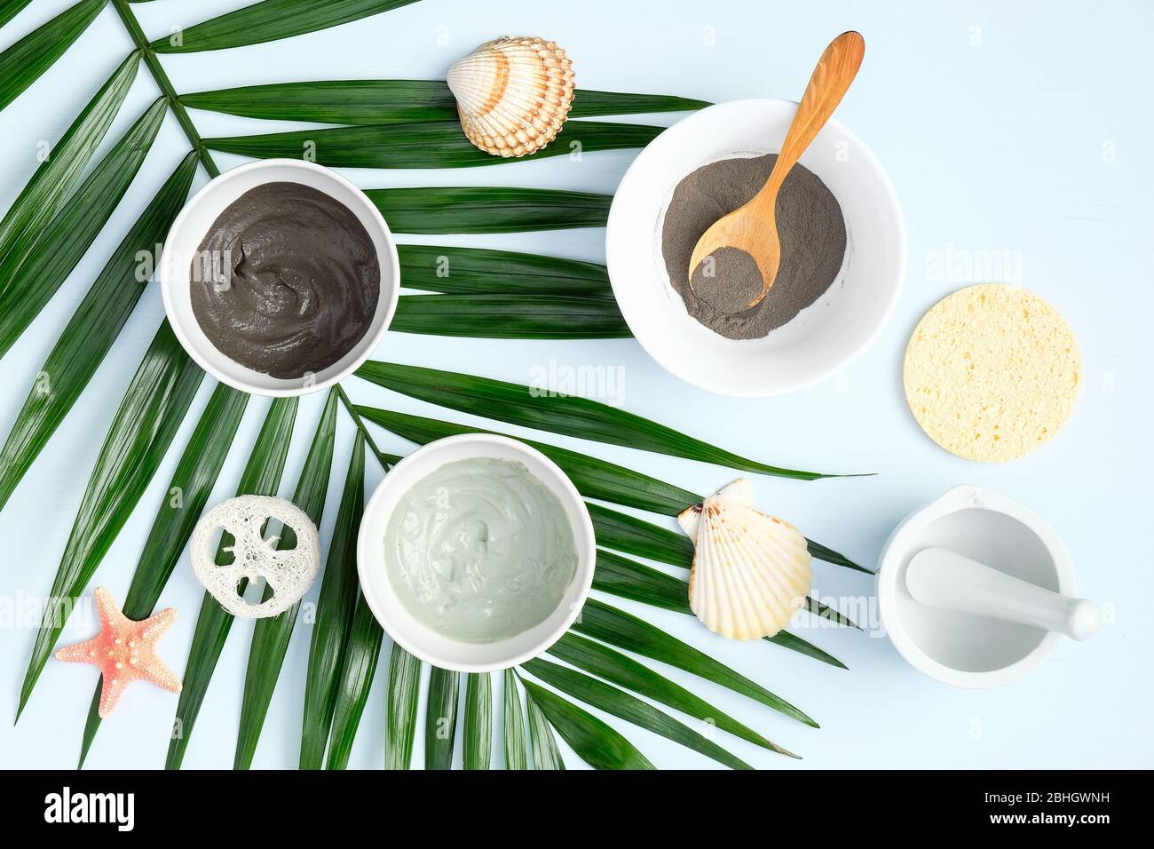 Face clay masks in bowls with tropical palm leaf, top view. Facial ...