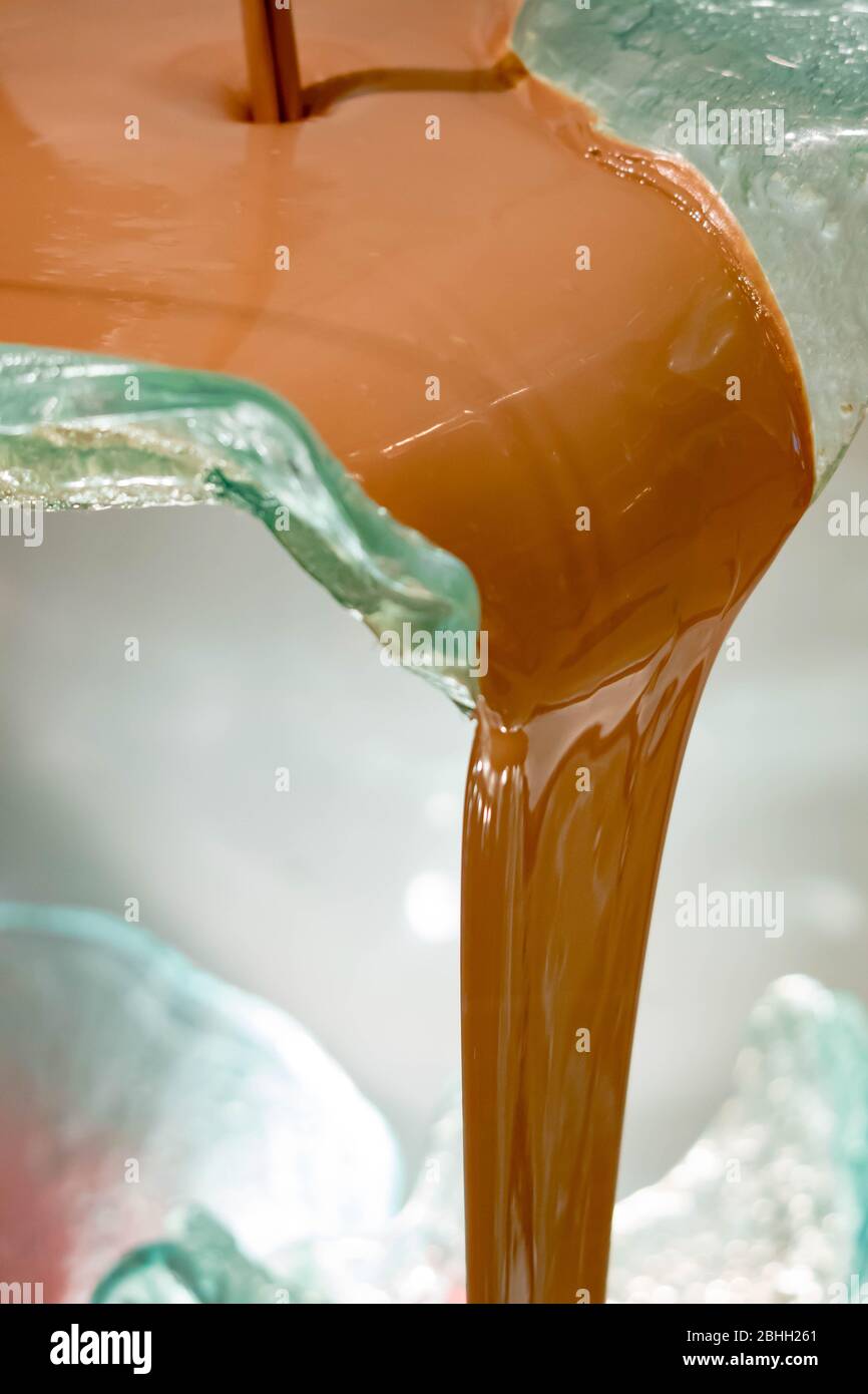 Chocolate flowing on a glass container. Chocolate fountain flowing ...