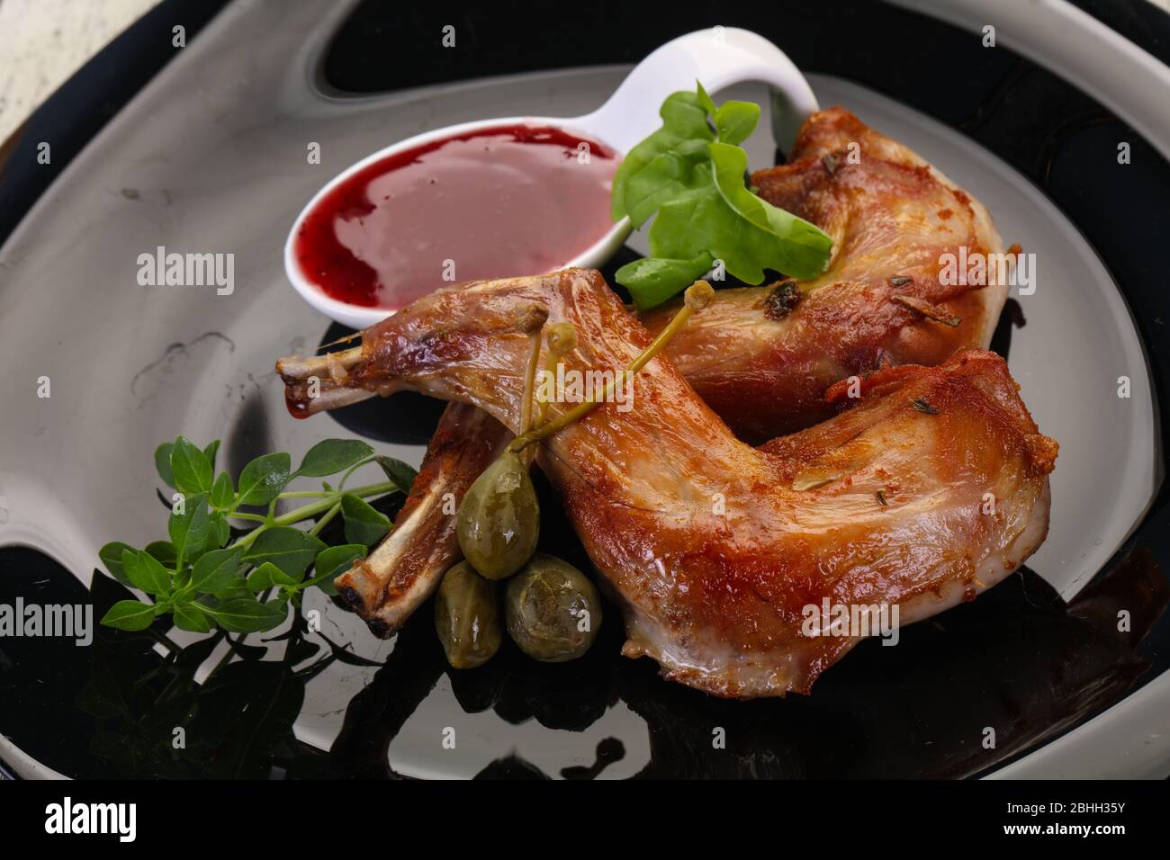 Roasted rabbit legs with cowberry sauce Stock Photo - Alamy