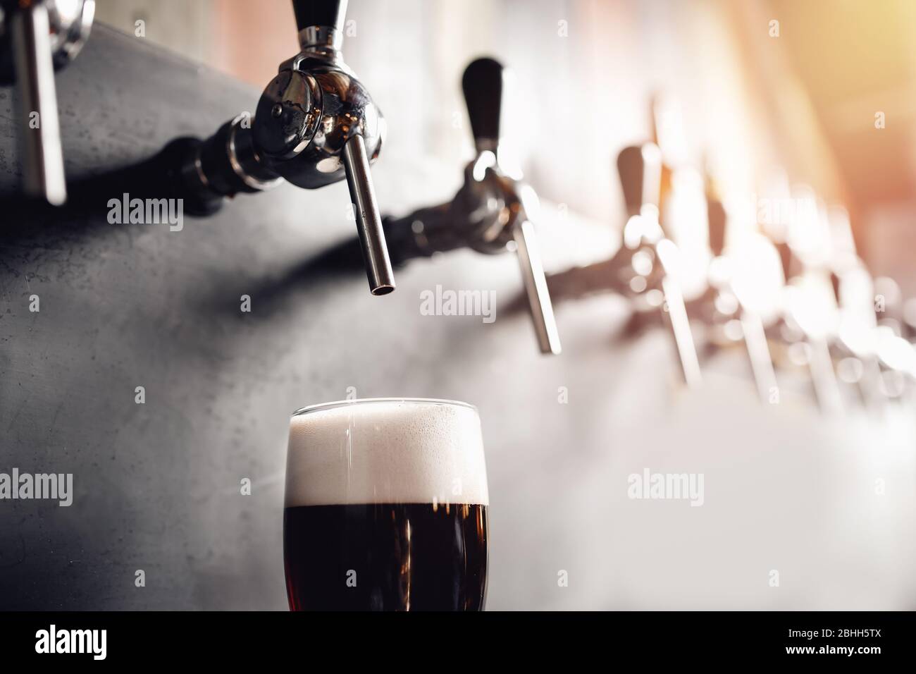 Dark Draft cold beer pour in glass from crane in pub Stock Photo - Alamy