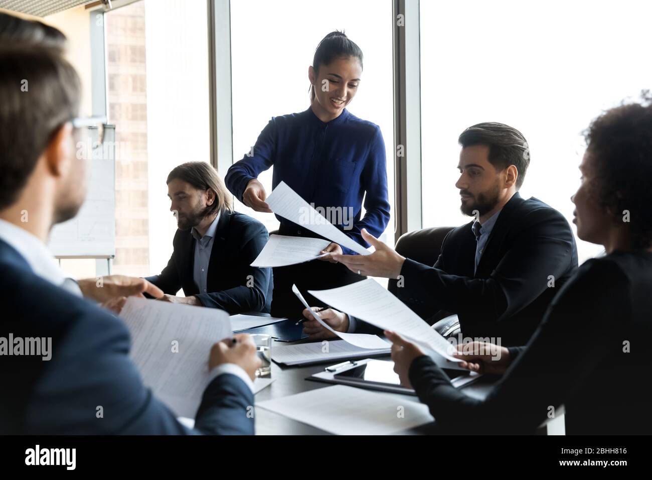 Smiling businesswoman coach giving handout material to employees at ...