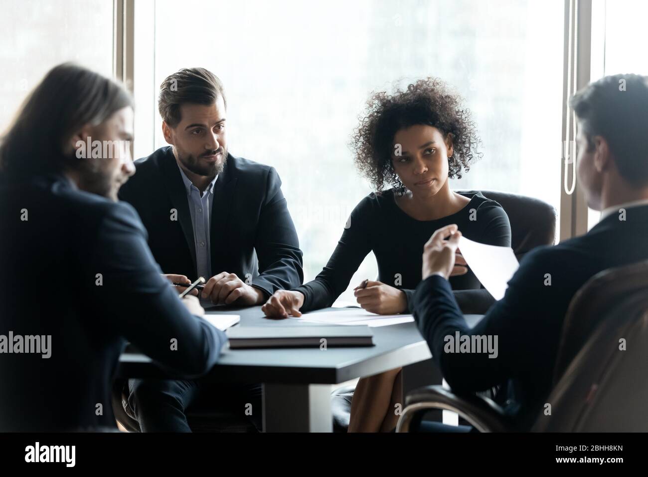 Serious diverse business partners discussing project strategy at ...