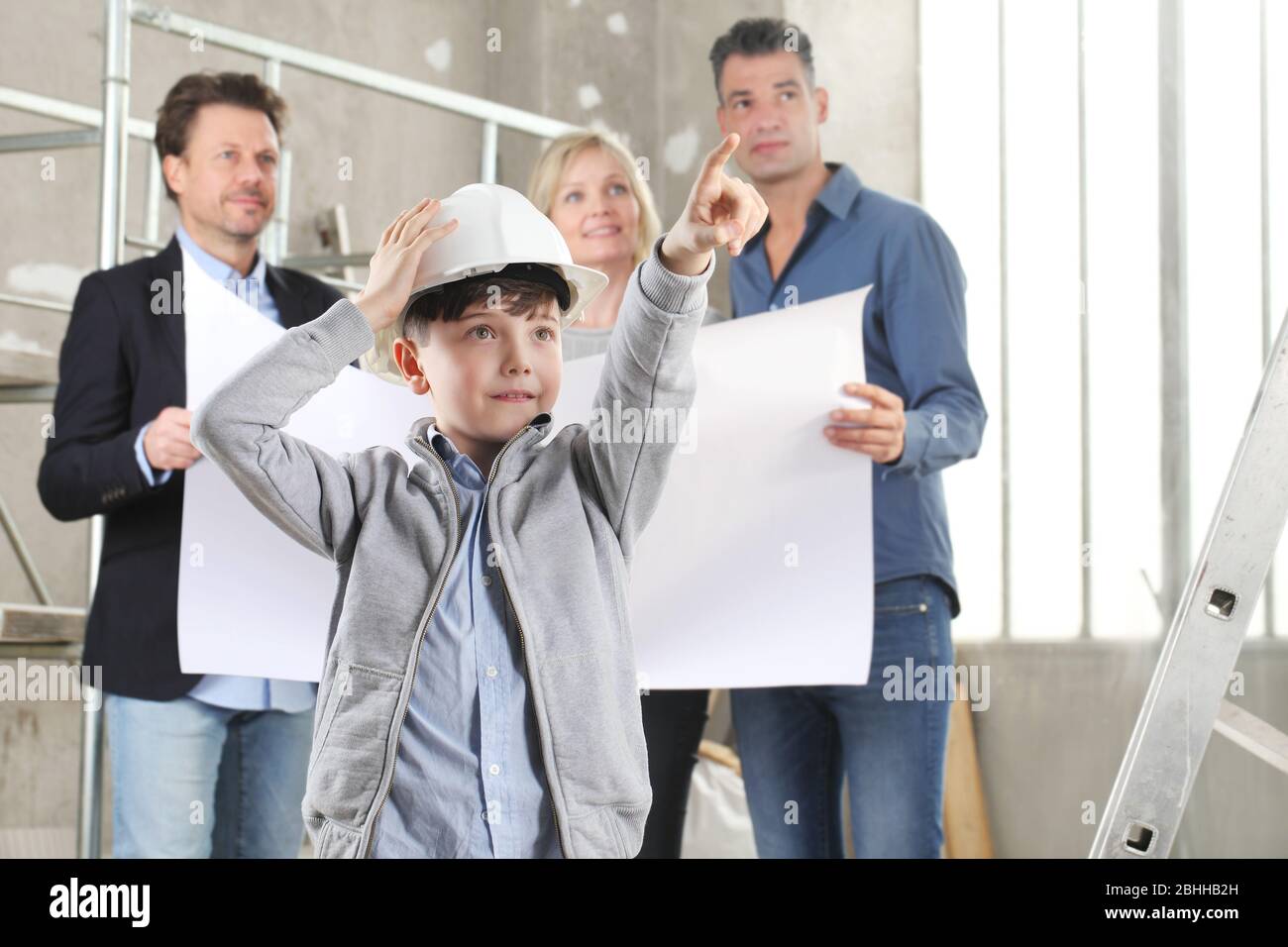 Architect showing house design plans to a family with child pointing ...