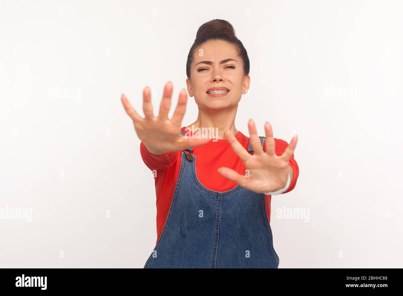 Stop, I'm afraid! Portrait of scared girl with hair bun in denim ...