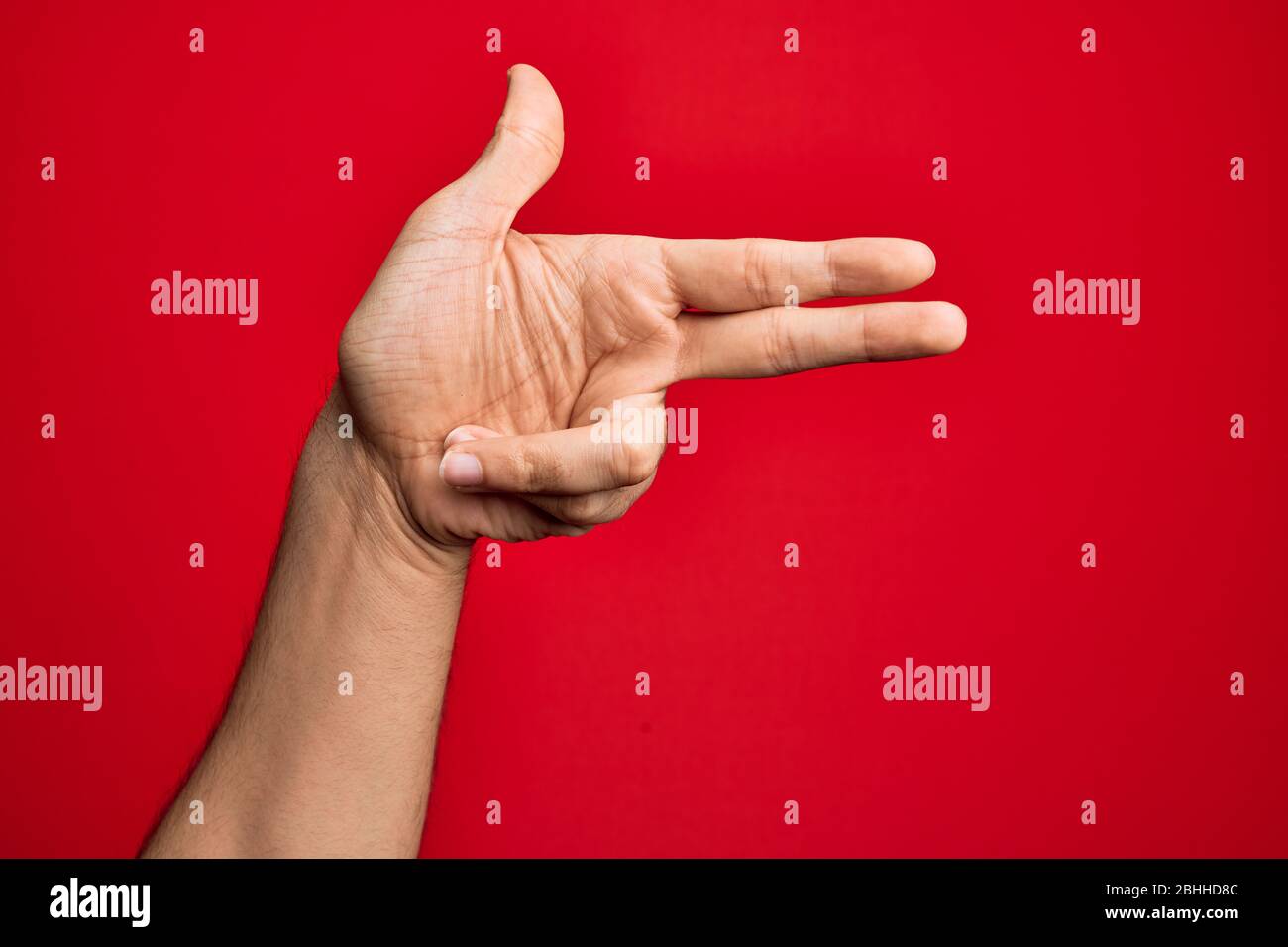 Hand of caucasian young man showing fingers over isolated red ...