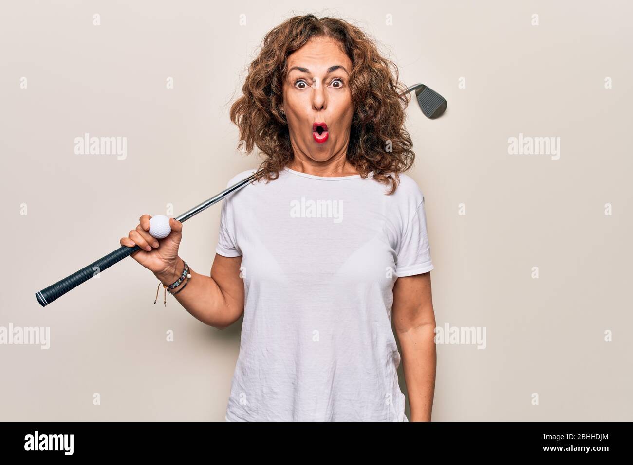 Middle age beautiful sportswoman playing golf using stick and ball over ...