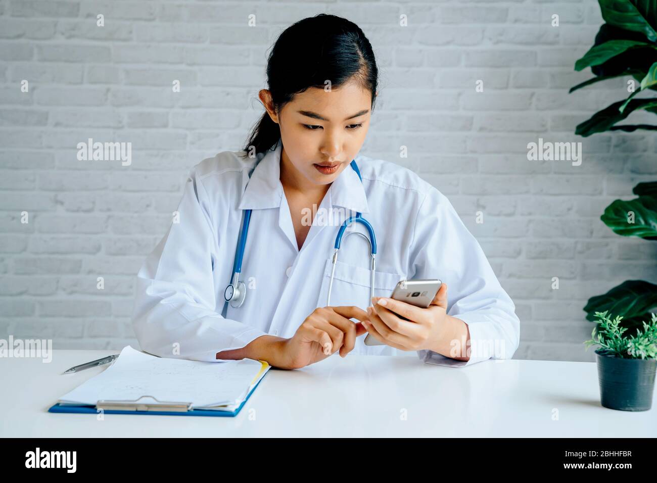 Young Asian female Doctor using a mobile phone at hospital. Healthcare ...