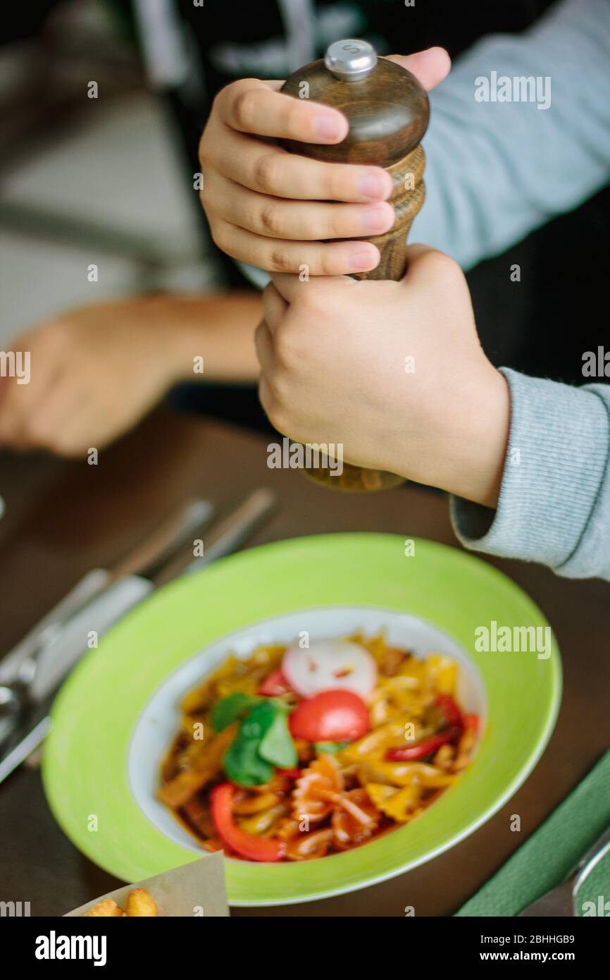 Kid hands and pepper grinder over the plate with food, great image for ...