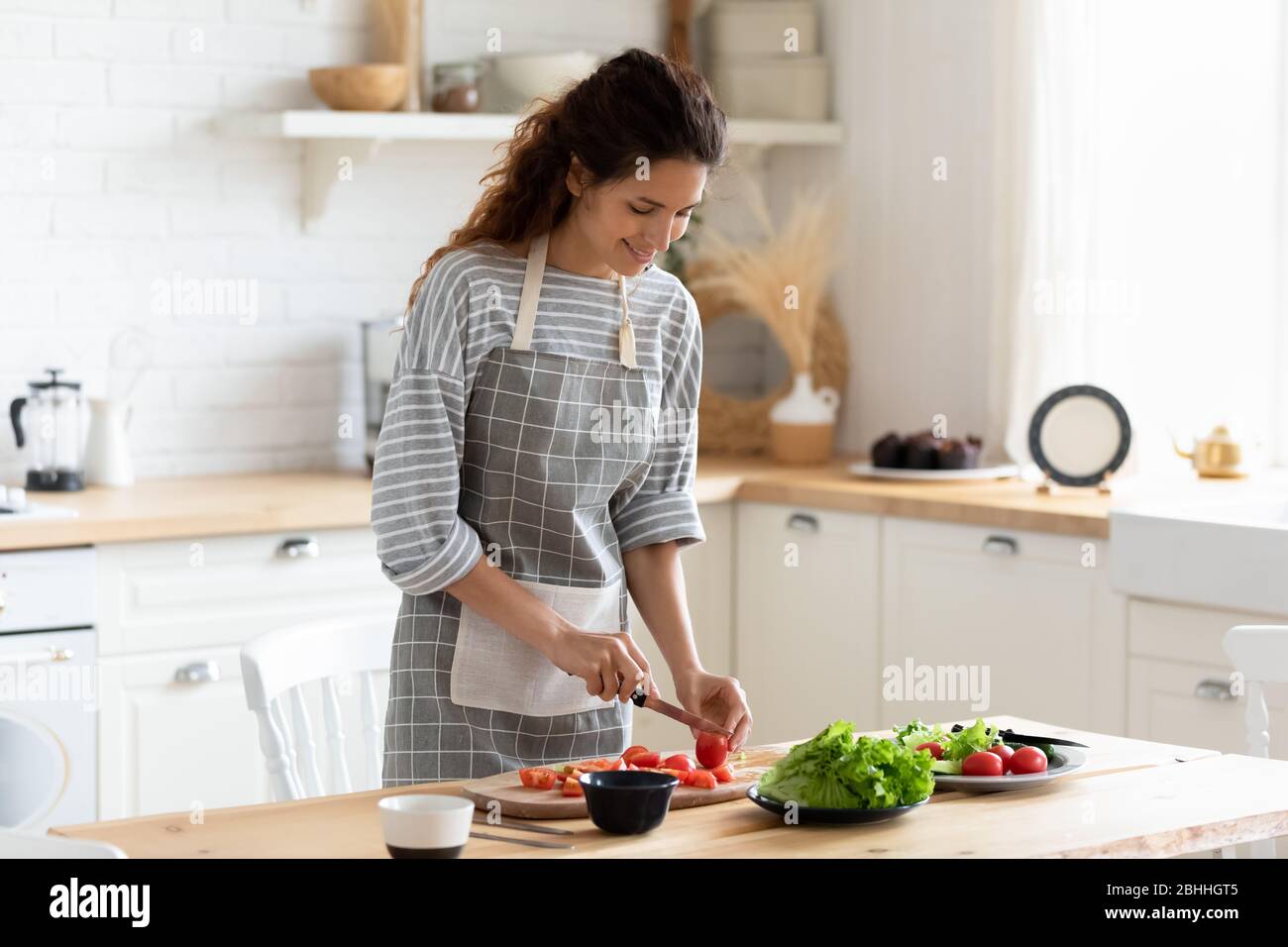 Smiling attractive young woman chopping fresh colorful vegetables Stock ...