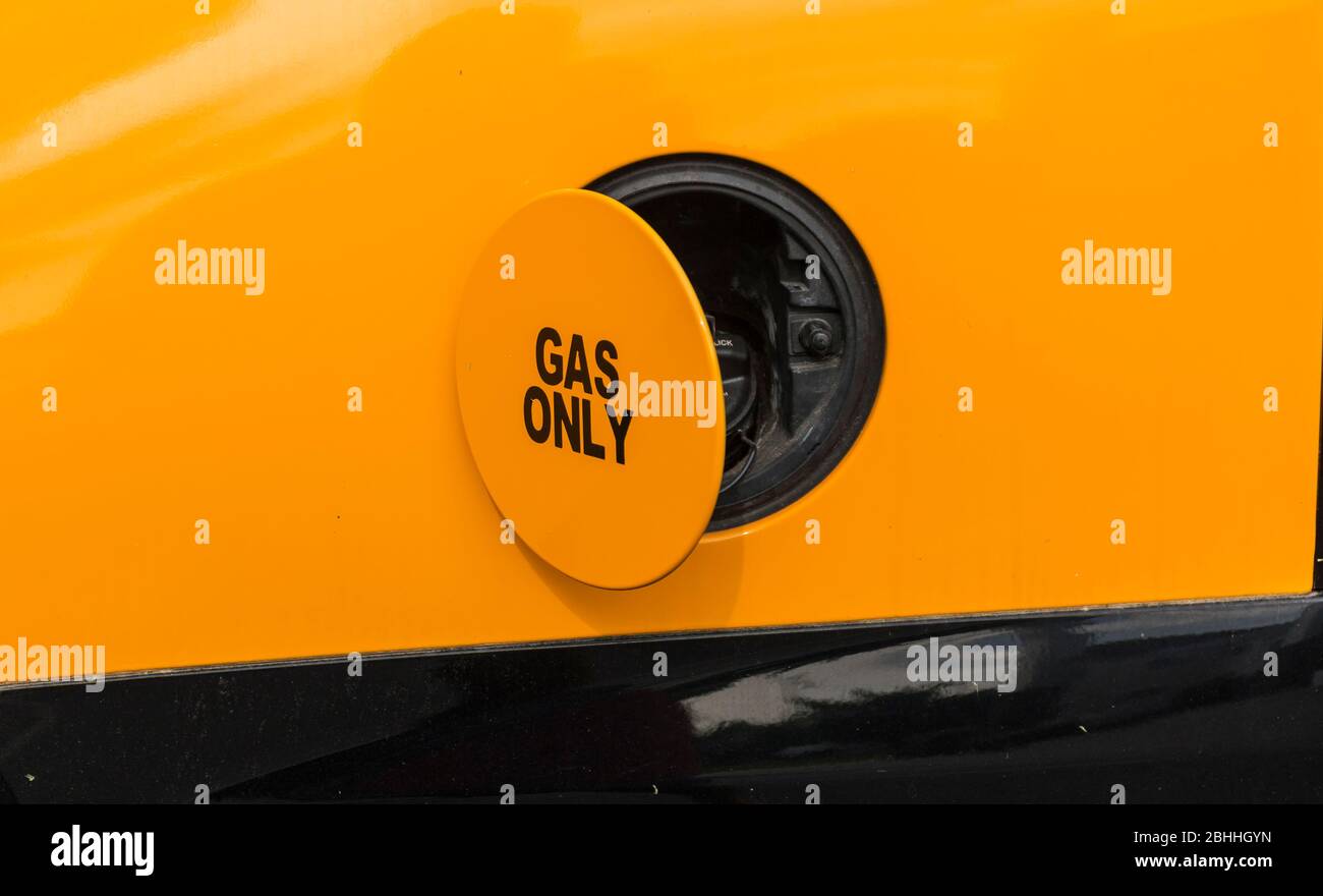 A yellow bus is powered by gas and the gas tank has gas only written on ...