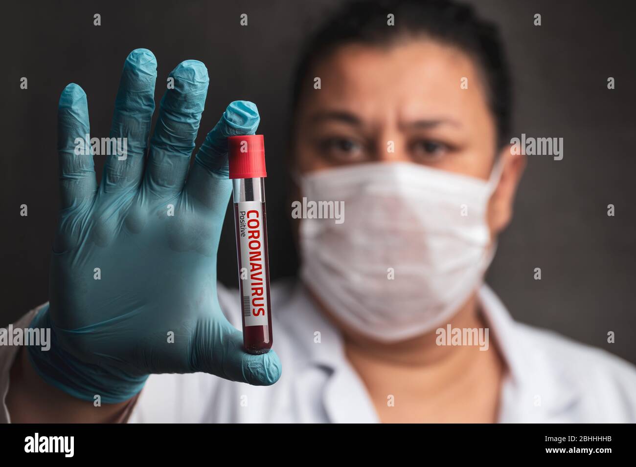 Nurse wearing respiratory mask holding a positive blood test result for ...