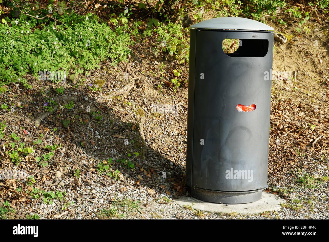 a metal garbage bin on a hiking trail with supply of plastic bag for ...