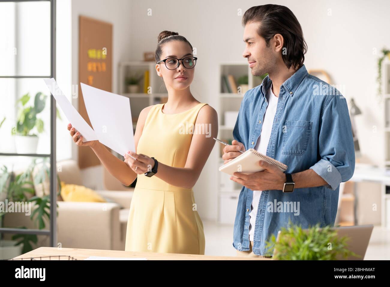 Young creative team comparing sketches while working on design in ...