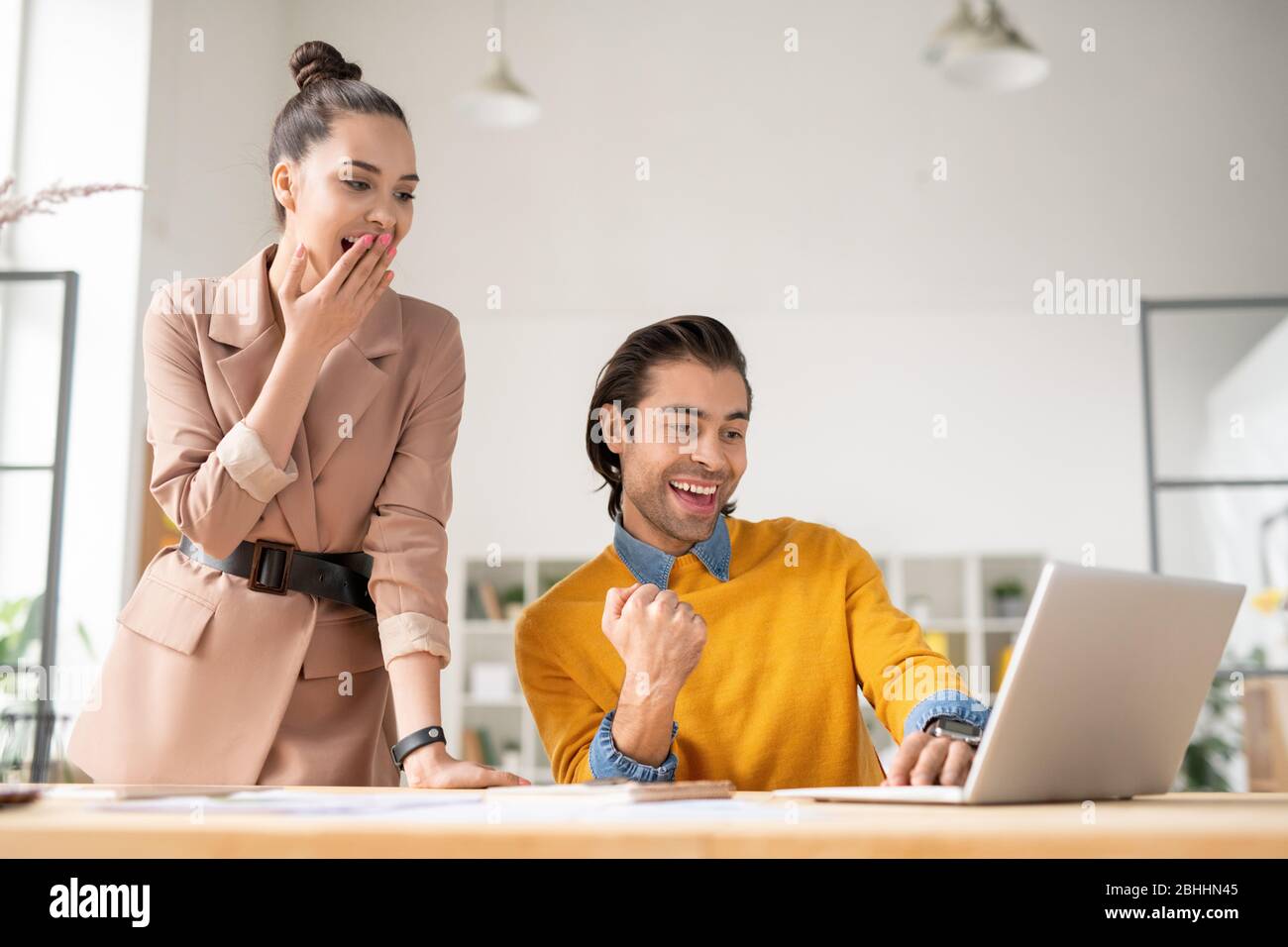 Excited young managers looking at laptop screen and making yes gesture ...