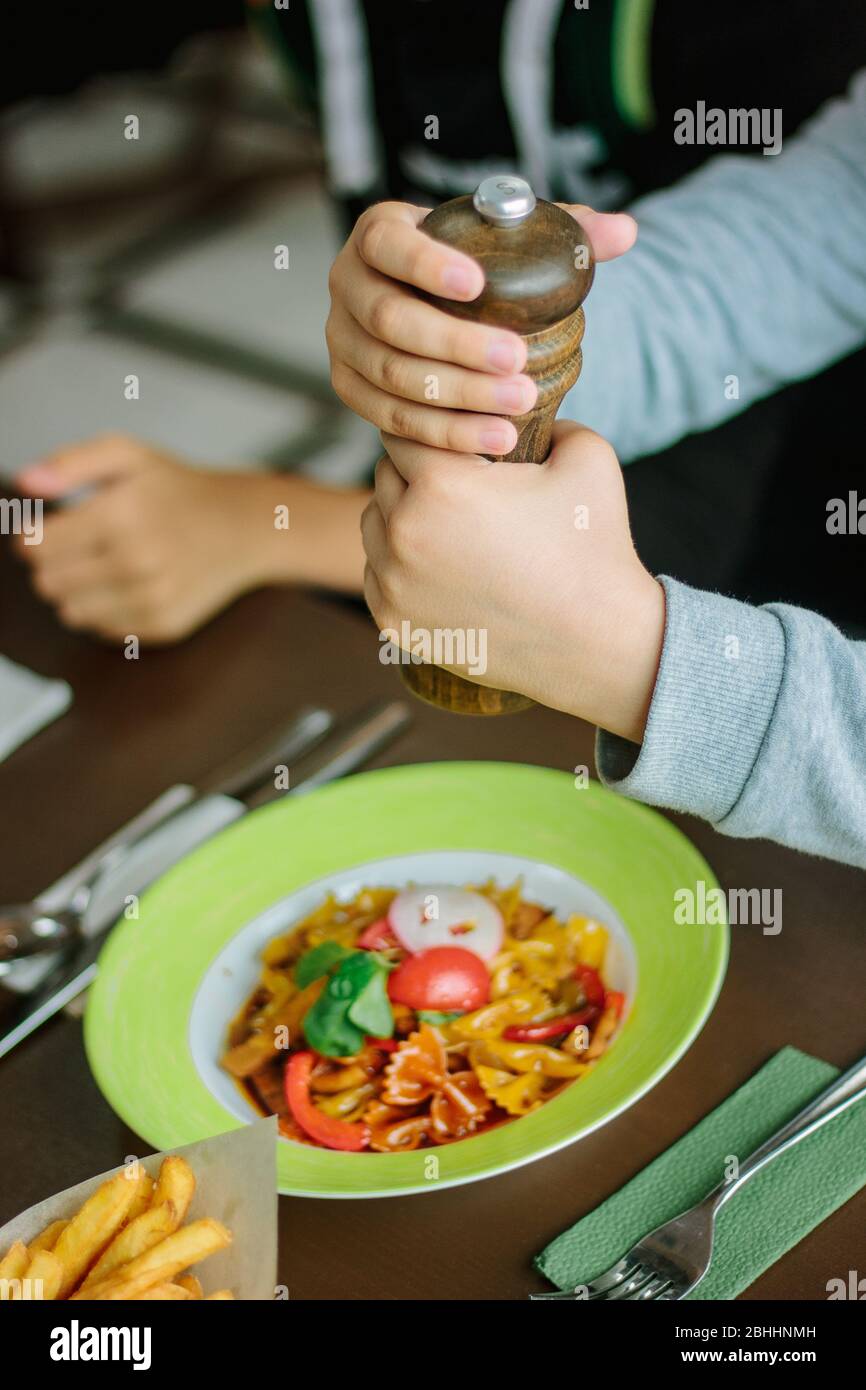 Kid hands and pepper grinder over the plate with food, great image for ...