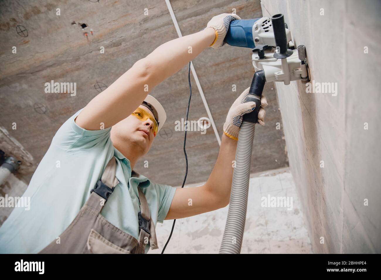 Builder worker cutting electrical chase in concrete wall with ...