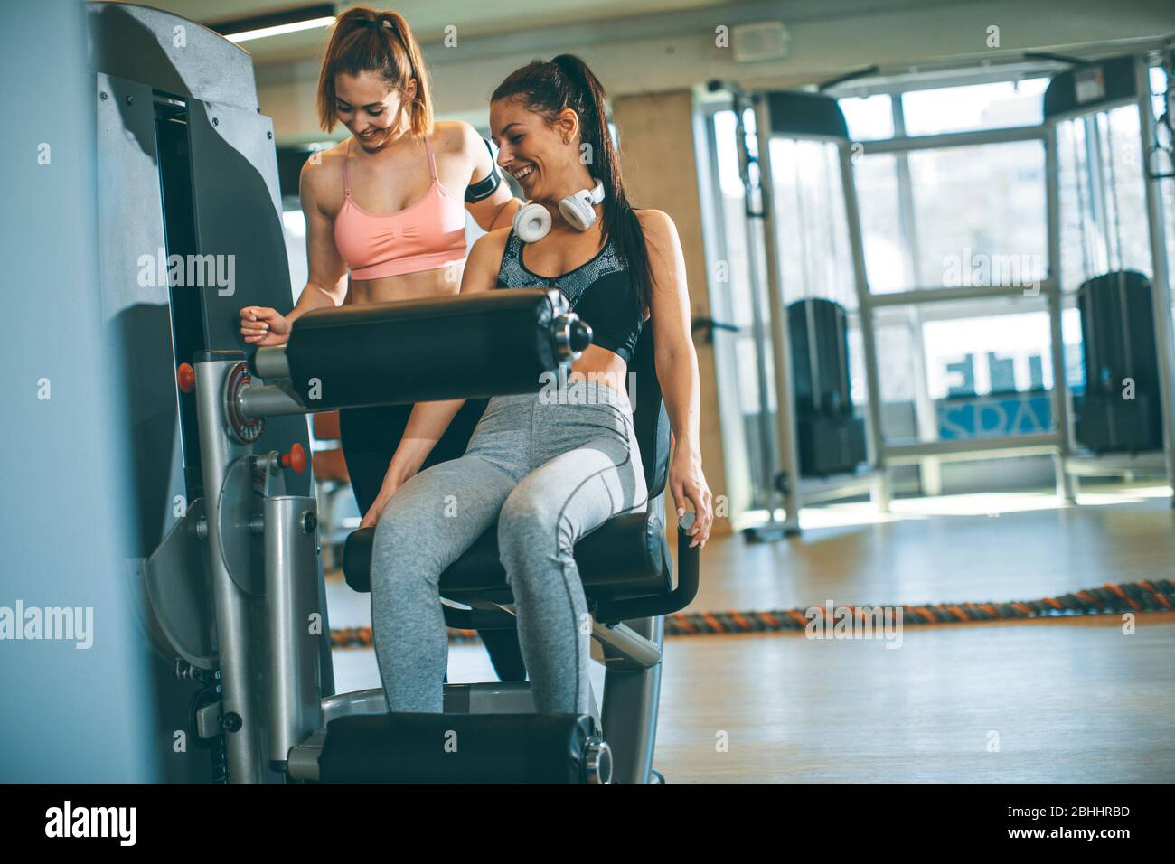 Pretty young woman having exercises on leg extension and leg curl ...