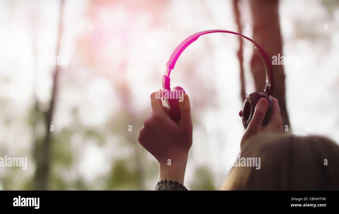 Young blonde woman,tourist framing the sun with the headphones in the ...