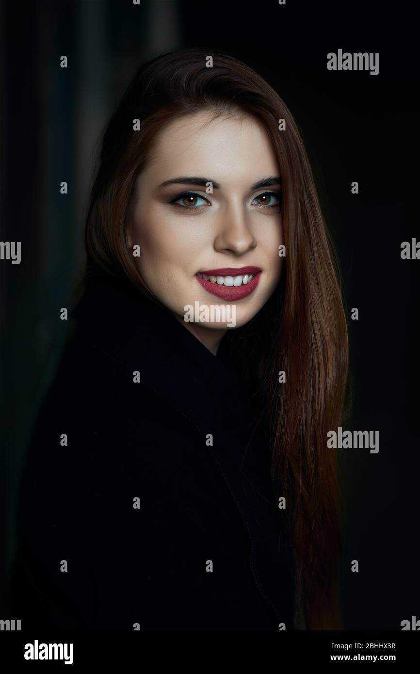 Low key portrait of beautiful girl with natural make up and red lips ...