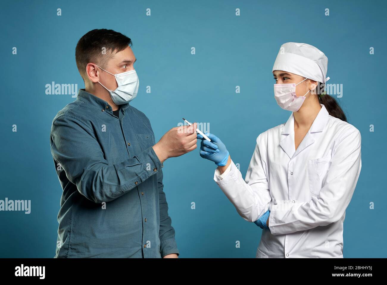 Young doctor measuring temperature of a patient with thermometer ...