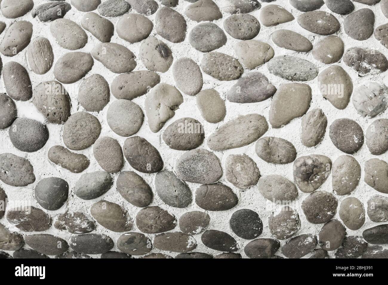Texture background-a wall made of round old stone. gray monochrome ...