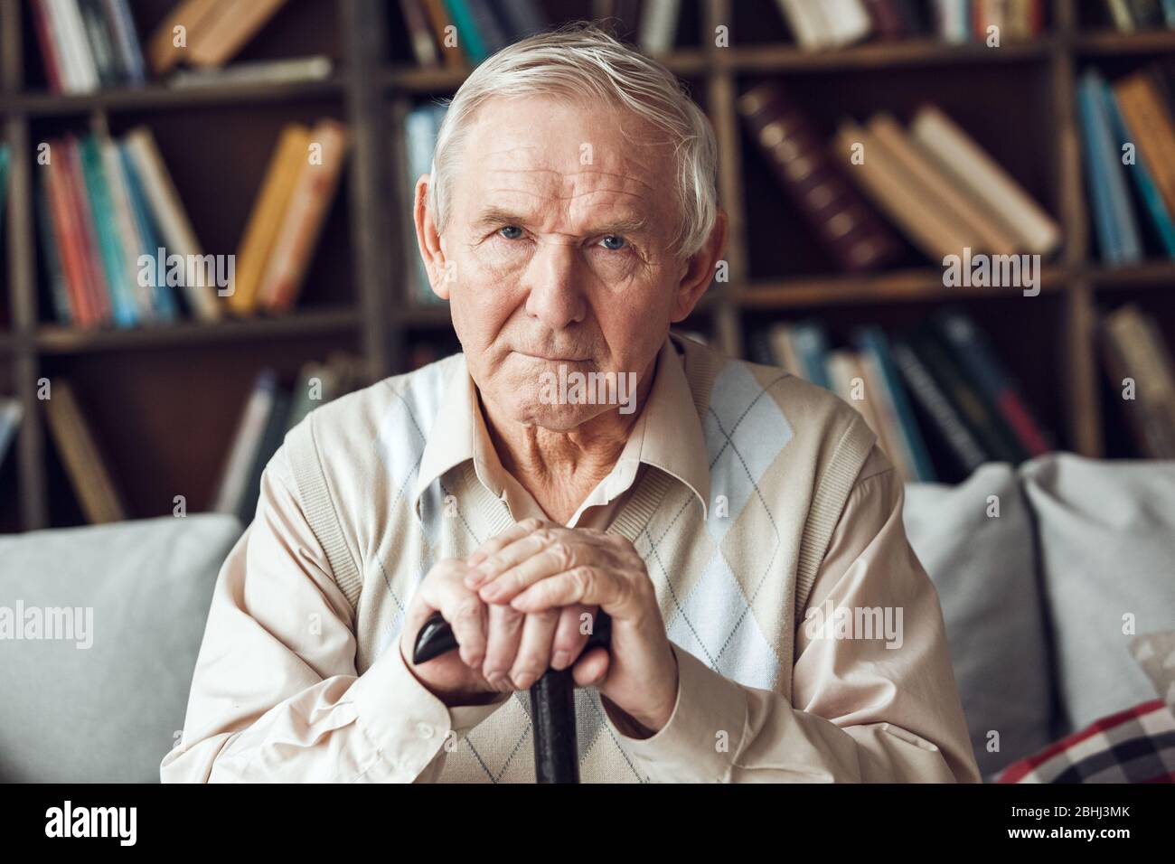 Senior man alone sitting at library with walking stick thinking Stock ...